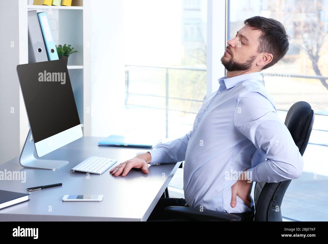 Posture concept. Man suffering from back pain while working with ...