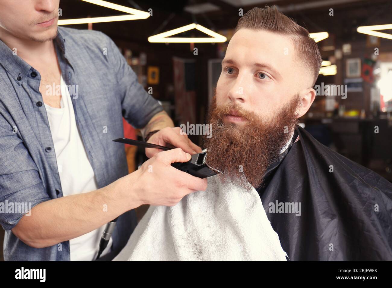 Hairdresser shaving client in barbershop Stock Photo - Alamy