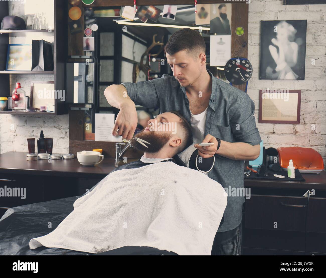 Hairdresser shaving client in barbershop Stock Photo - Alamy