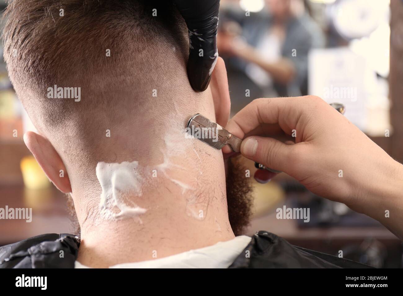 Hairdresser shaving client in barbershop Stock Photo - Alamy