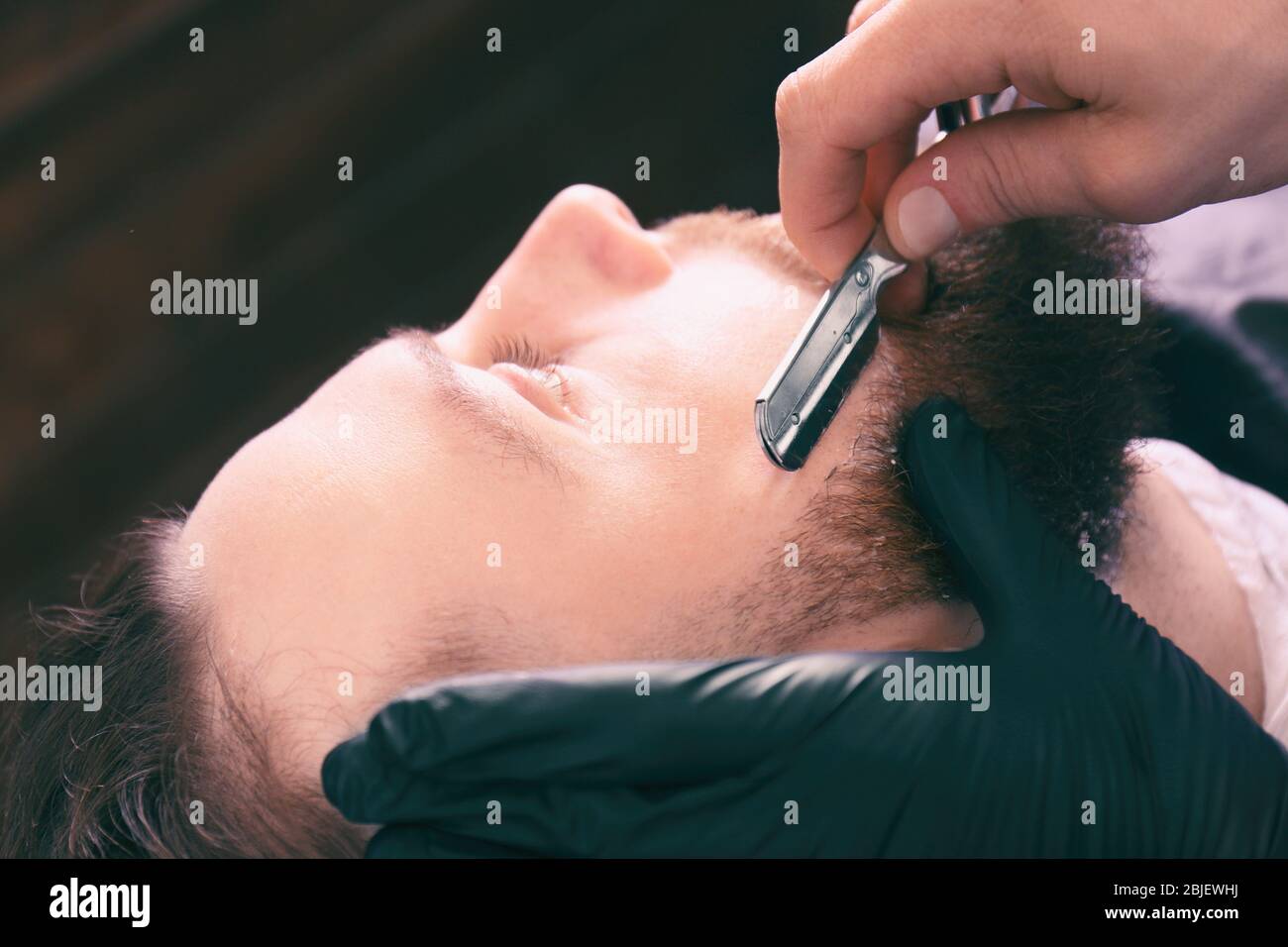 Hairdresser shaving client in barbershop Stock Photo - Alamy