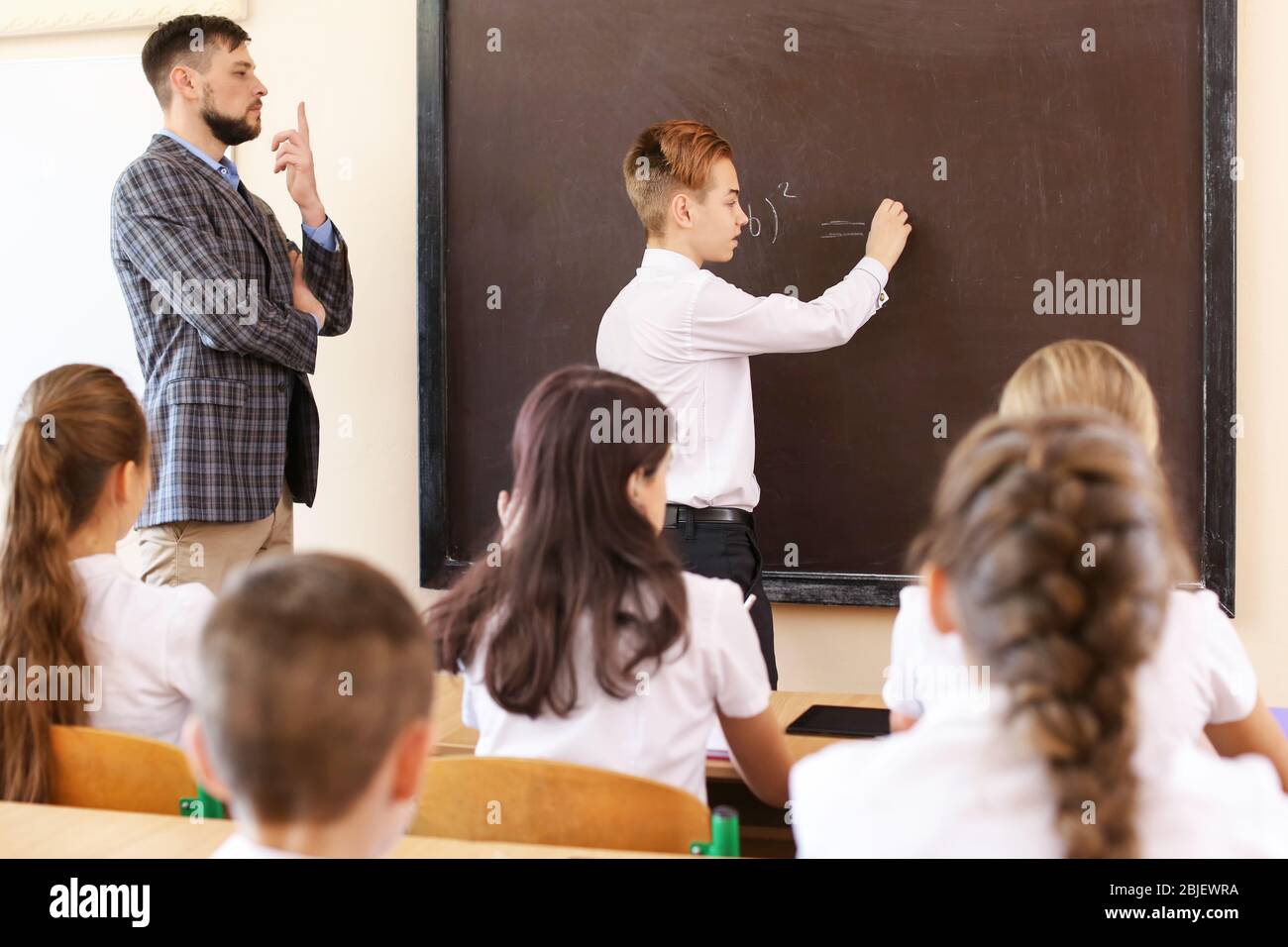 Pupil answering at blackboard in classroom Stock Photo - Alamy