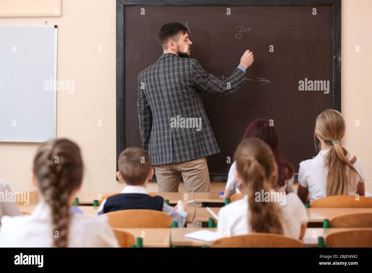 Pupils listening teacher in classroom Stock Photo - Alamy