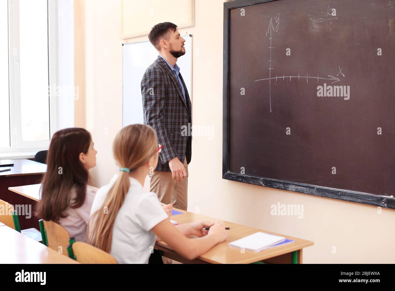 Pupils listening teacher in classroom Stock Photo - Alamy