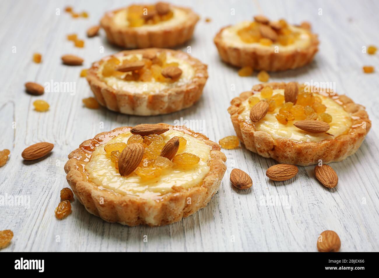 Delicious crispy tarts with almond and raisins on wooden background ...