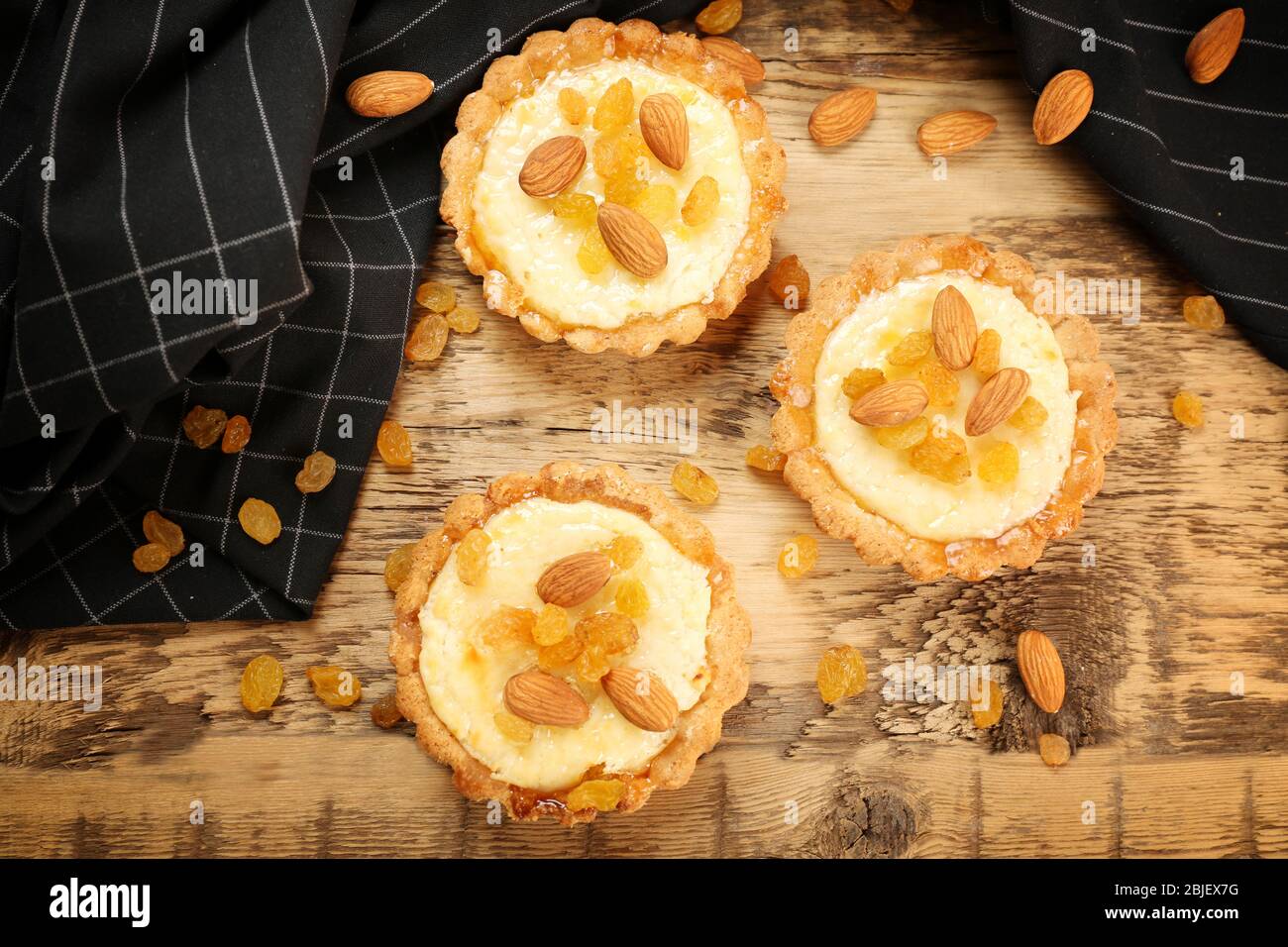 Delicious crispy tarts with almond and raisins on wooden table Stock ...