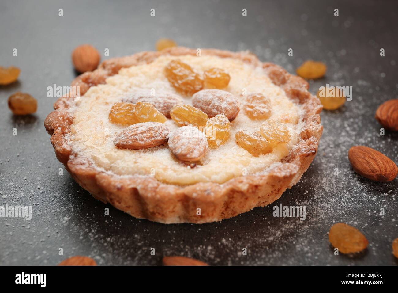 Delicious crispy tart with sugar powder, almond and raisins on table ...