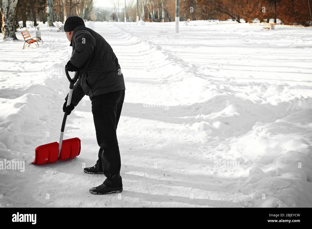 Man removing snow with red shovel Stock Photo - Alamy