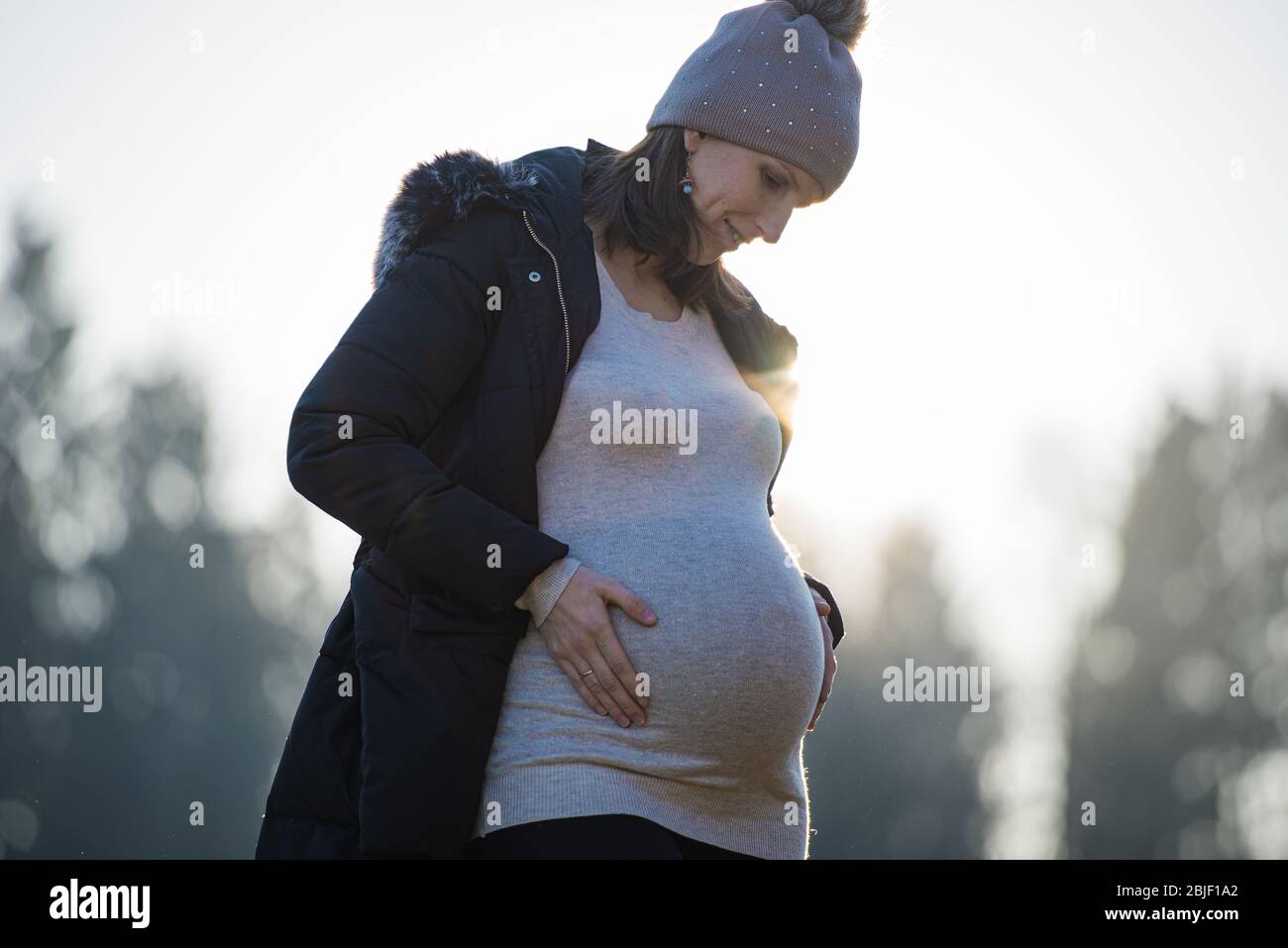 View from below of a pregnant young woman standing outside in nature ...