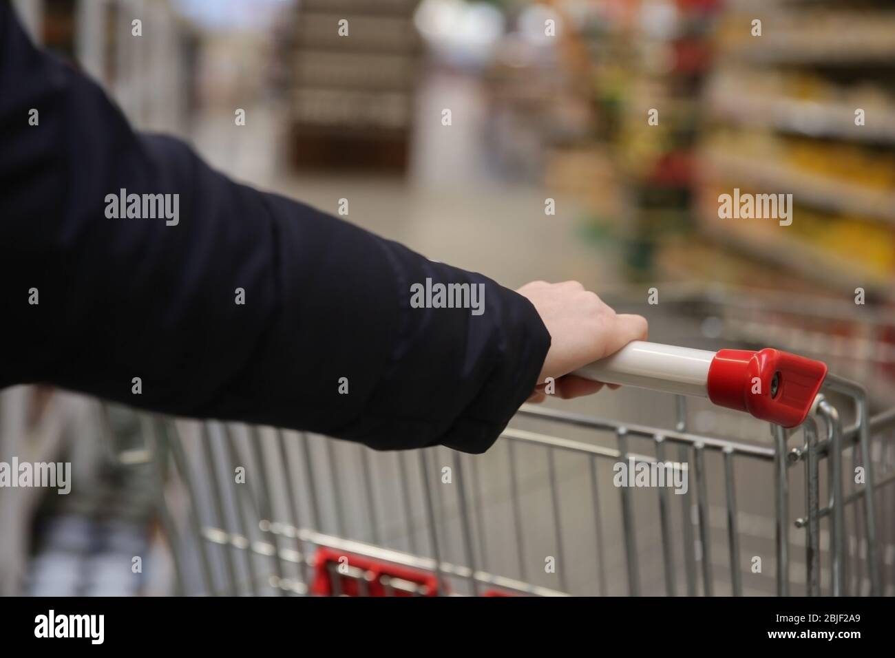 Female hands holding supermarket trolley Stock Photo - Alamy