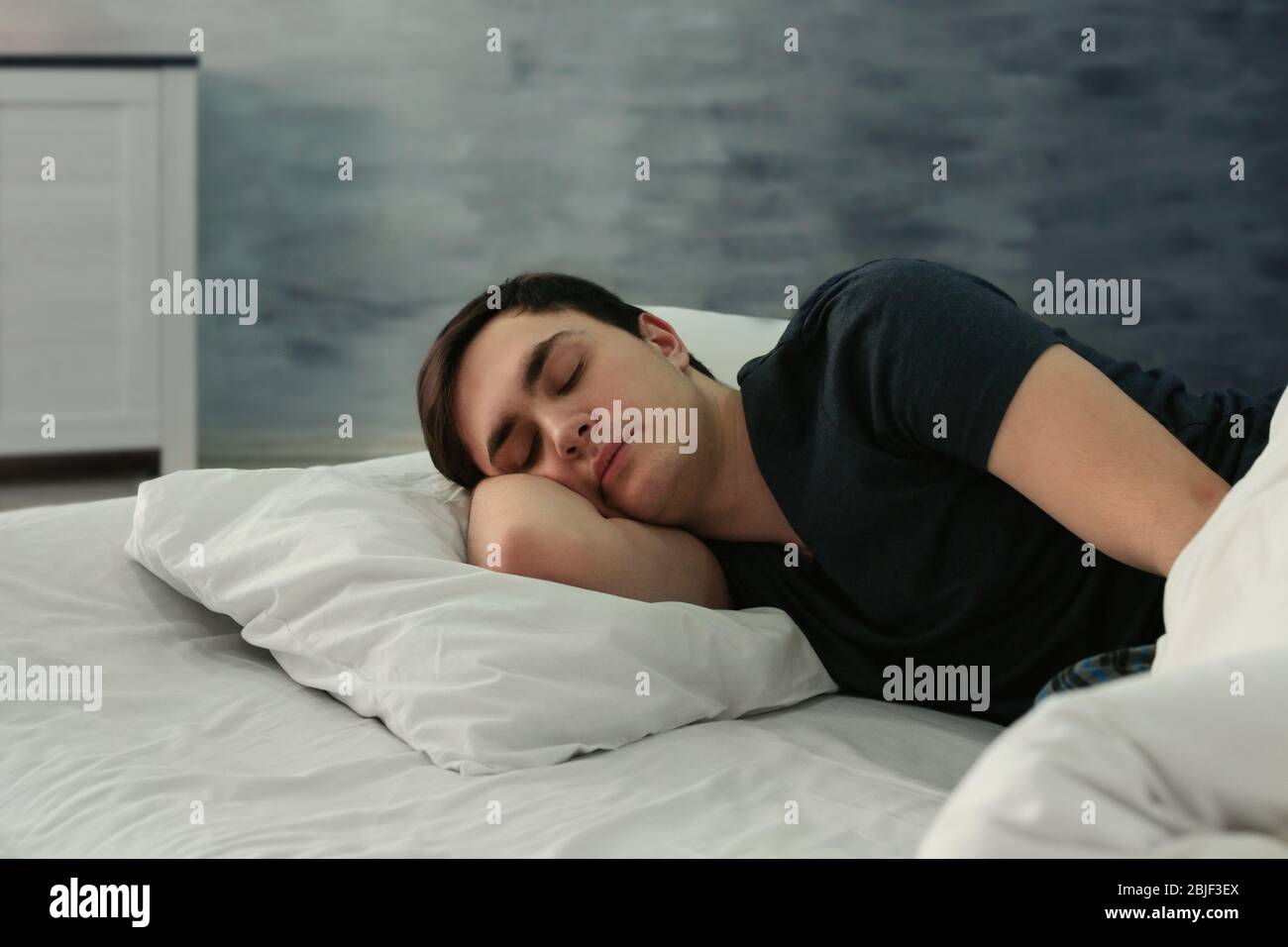 Young tired man sleeping in bed at home Stock Photo - Alamy