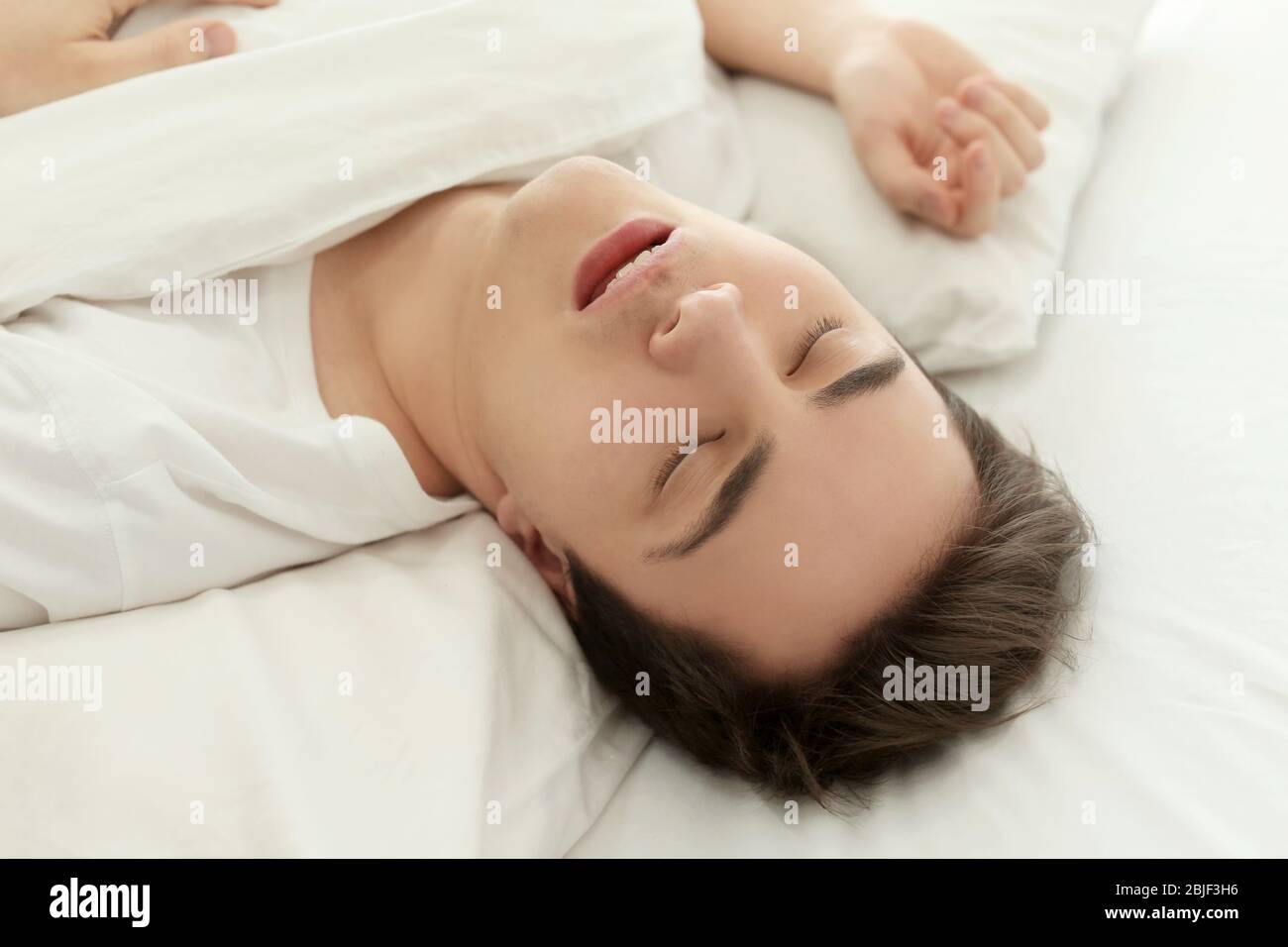 Tired young man sleeping in bed at home Stock Photo - Alamy