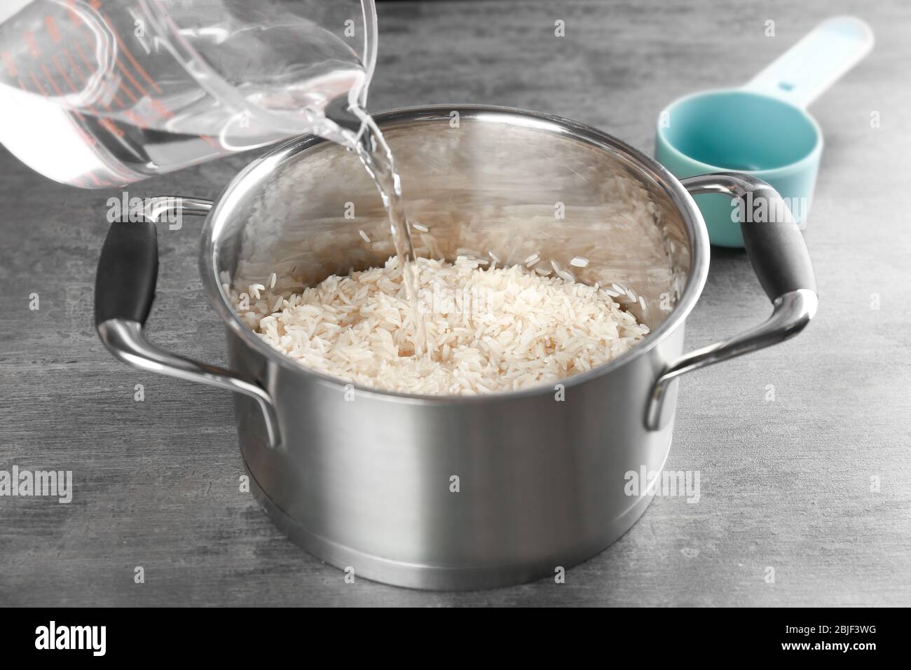 Cooking concept. Pouring water in saucepan with rice Stock Photo - Alamy