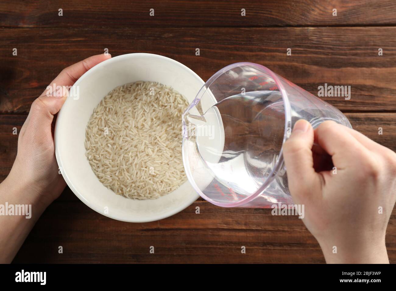 Cooking concept. Pouring water in bowl with rice Stock Photo - Alamy