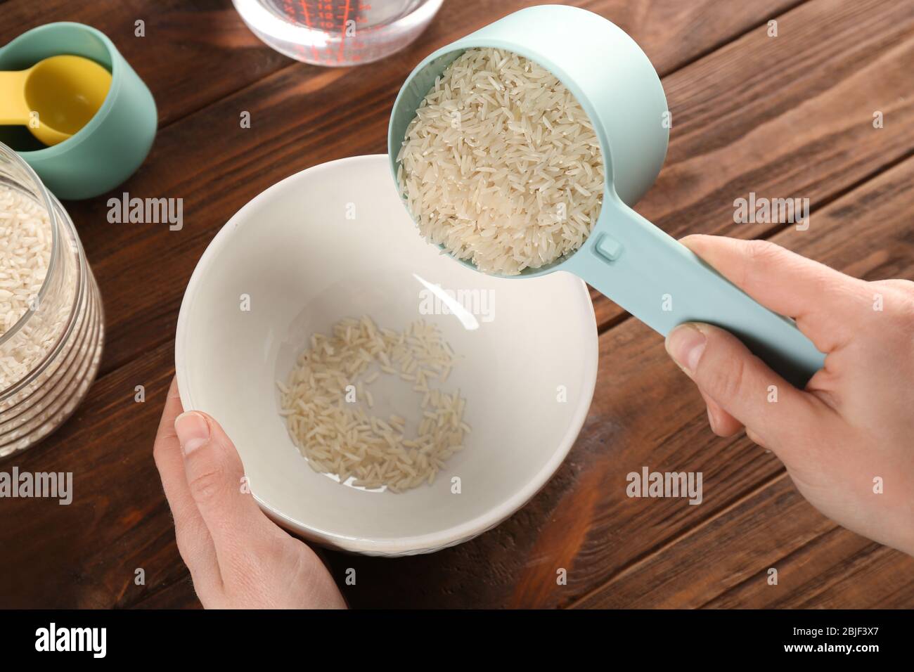 Cooking concept. Woman pouring rice from measuring scoop to bowl on ...