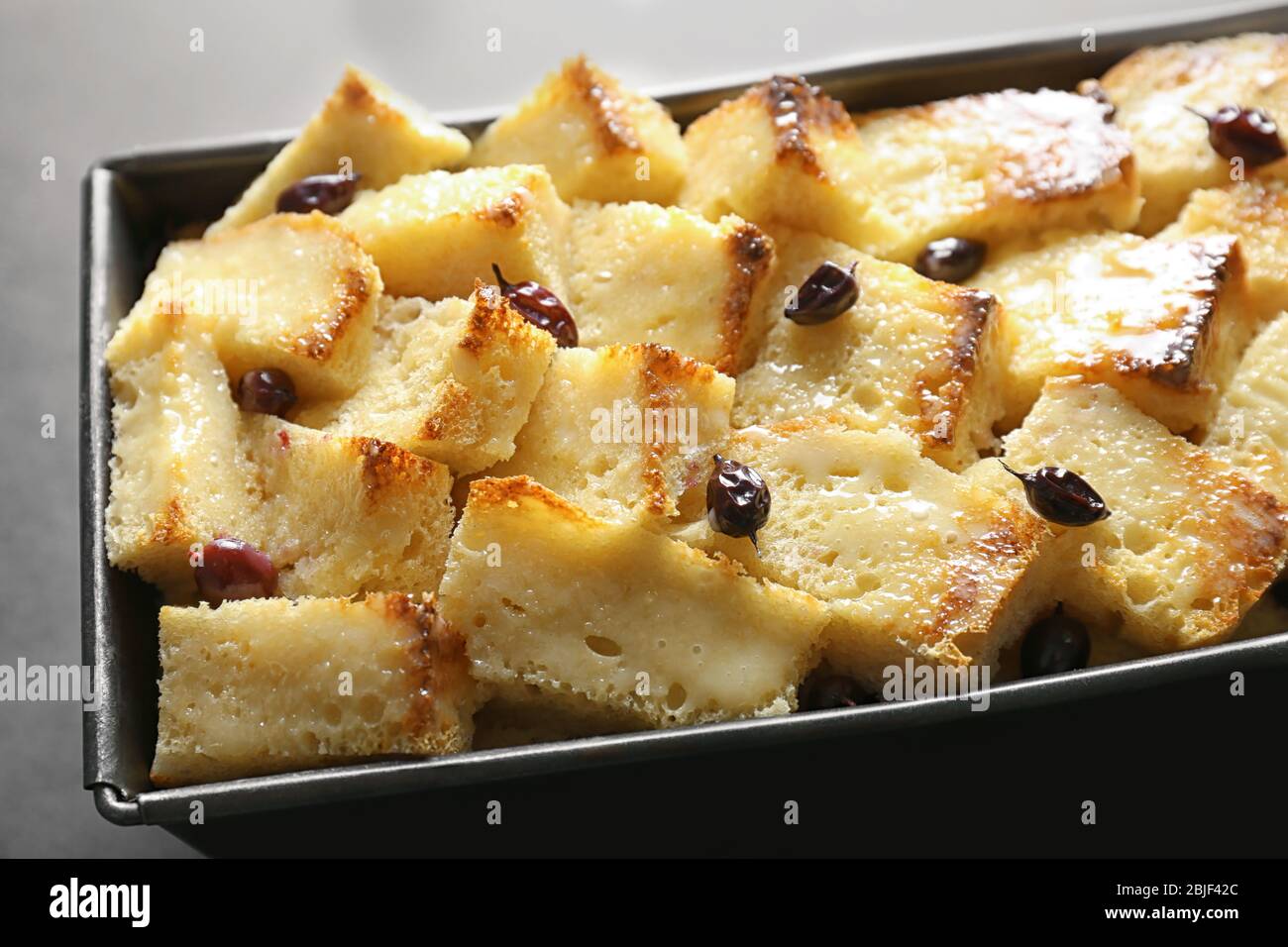 Delicious bread pudding with currant in baking dish on kitchen table ...
