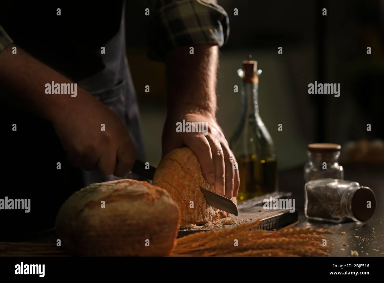 Man cutting bread on kitchen table, closeup Stock Photo - Alamy