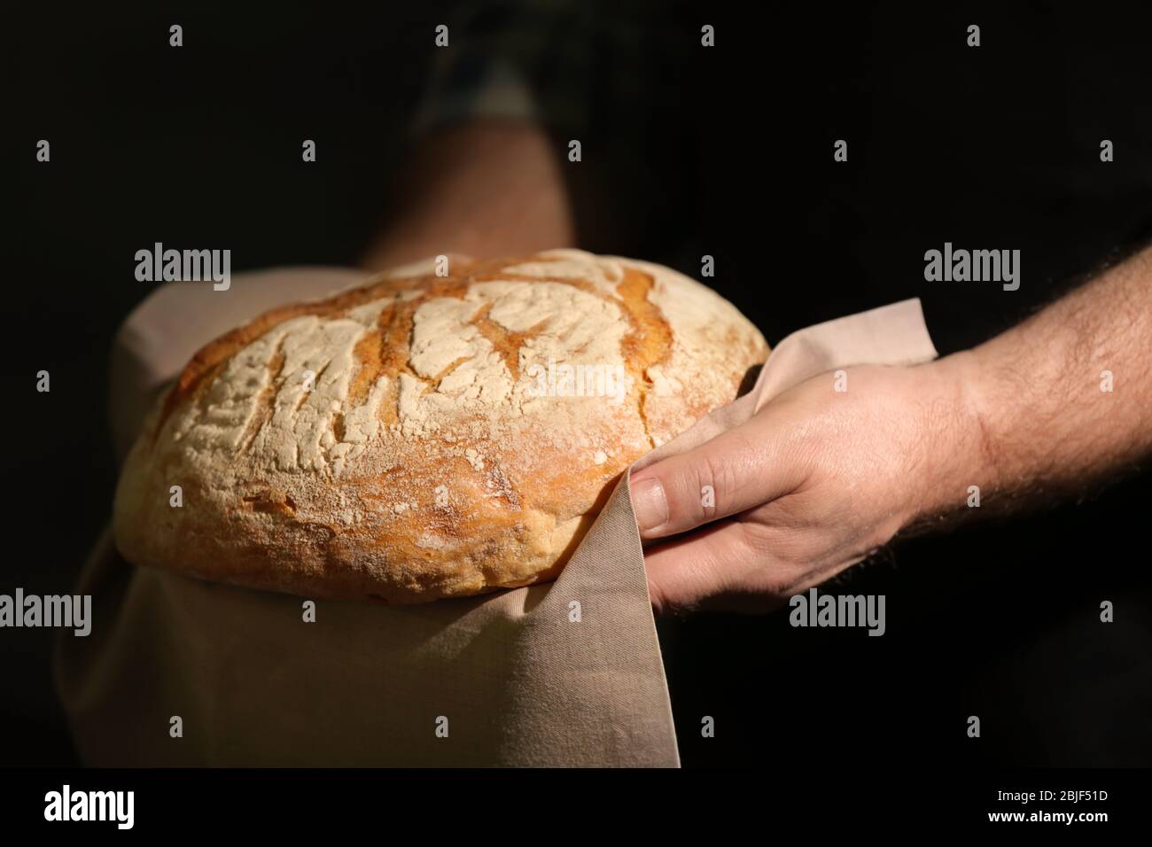 Male hands with loaf of bread on dark background, closeup Stock Photo ...