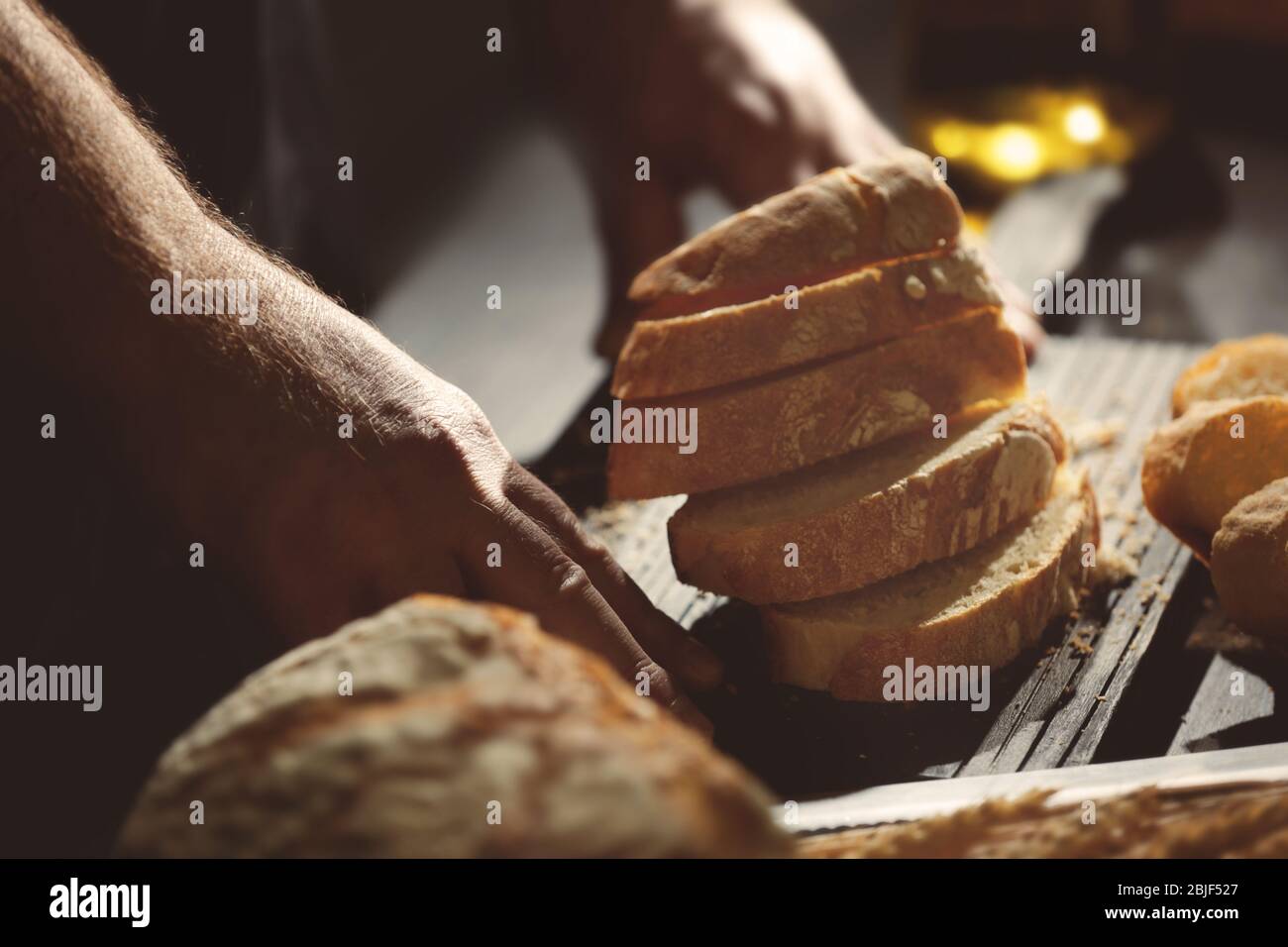 Man with cut bread in kitchen, closeup Stock Photo - Alamy