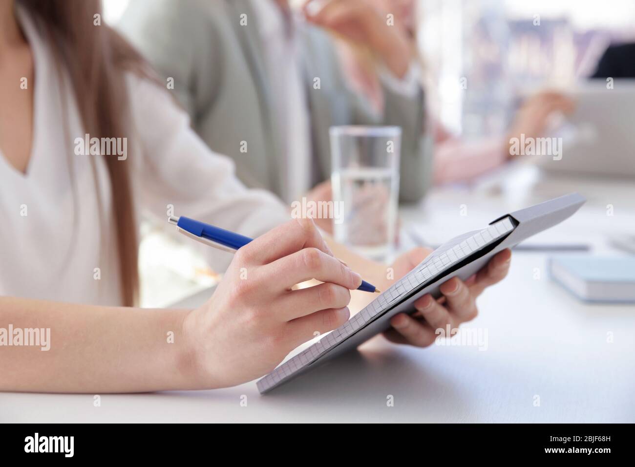 Woman making notes in notebook at business presentation Stock Photo - Alamy