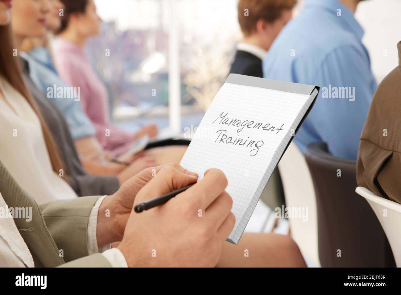 Man holding notebook with text MANAGEMENT TRAINING at business ...