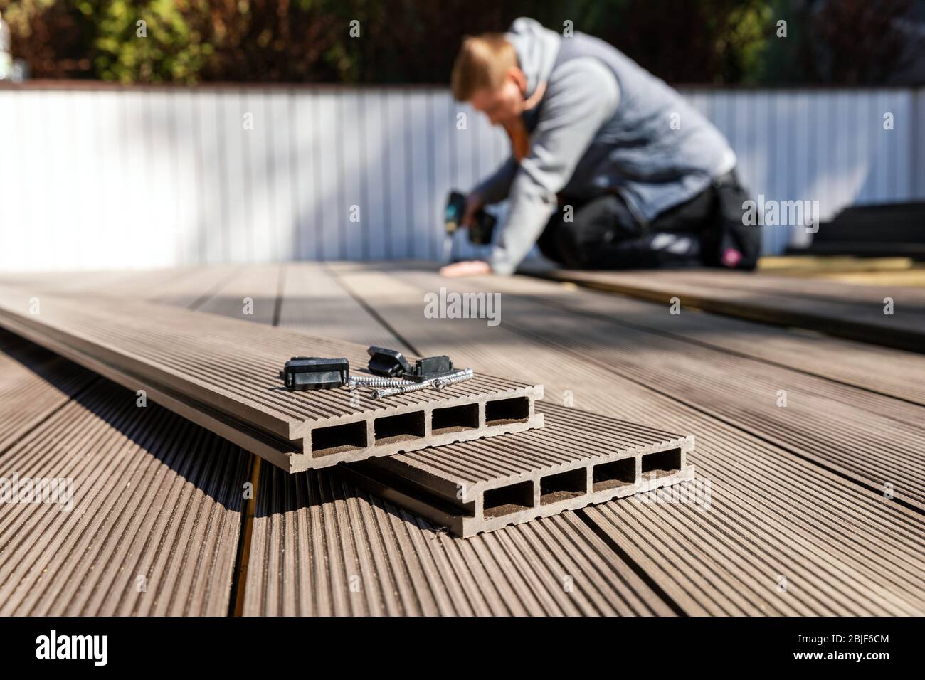 wpc terrace construction - worker installing wood plastic composite ...