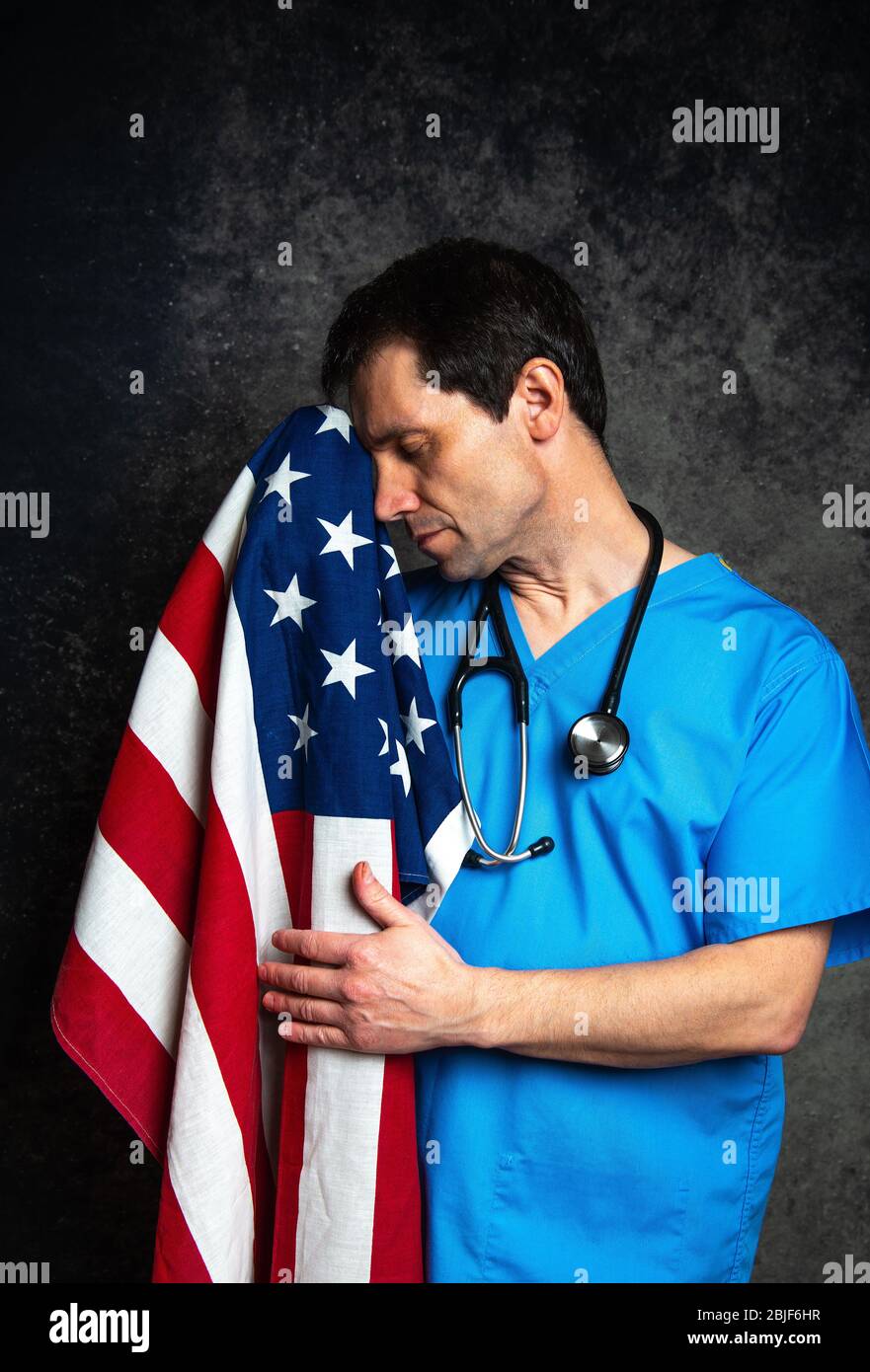 Sad/pensive male doctor in blue hospital scrubs with stethoscope ...