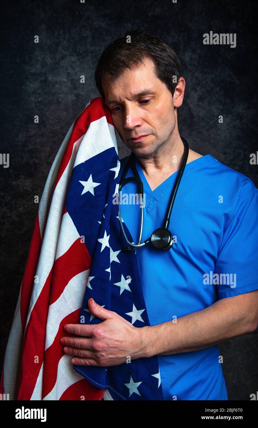 Sad/pensive male doctor in blue hospital scrubs with stethoscope ...
