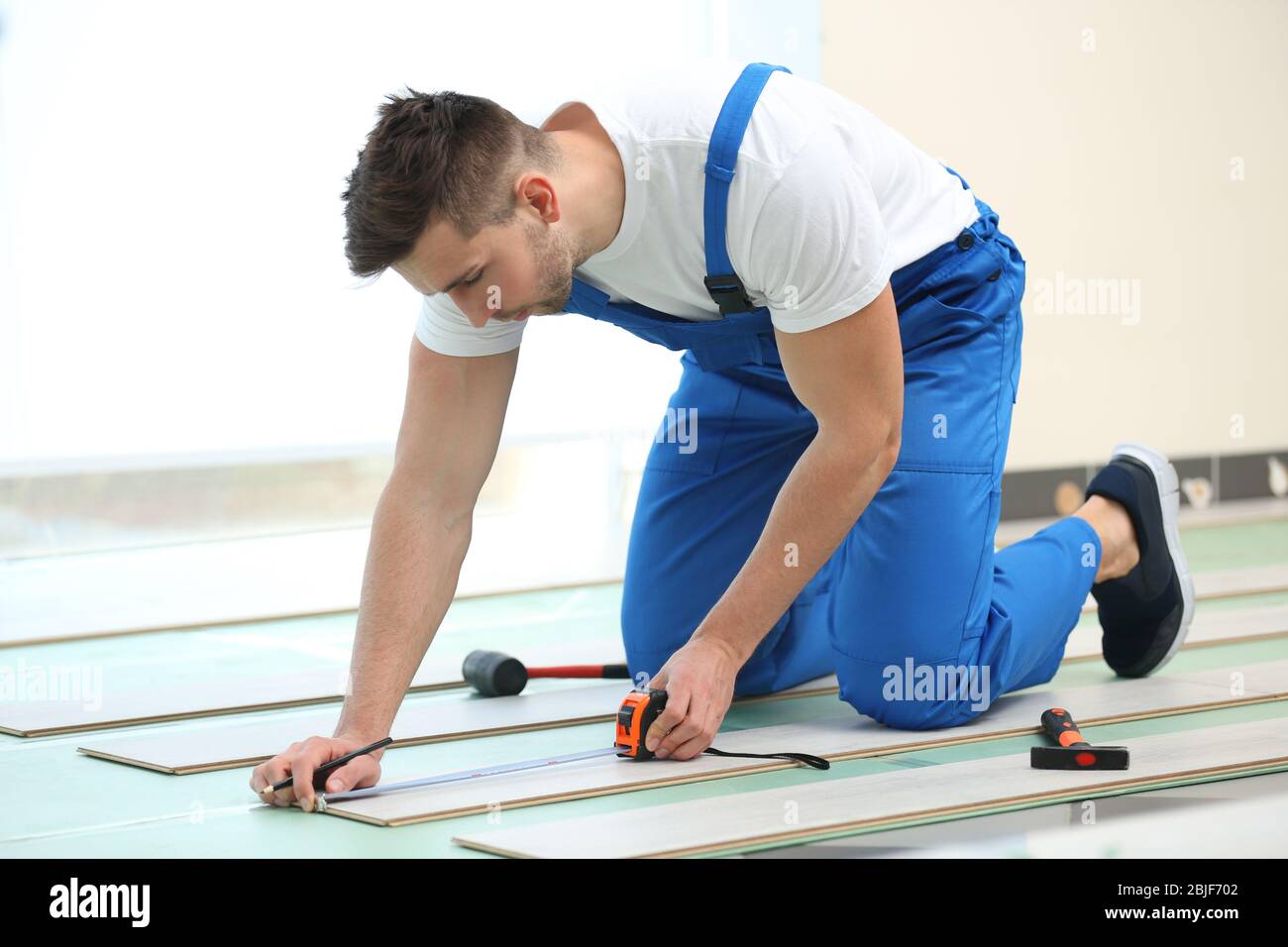Male worker installing laminate flooring Stock Photo - Alamy