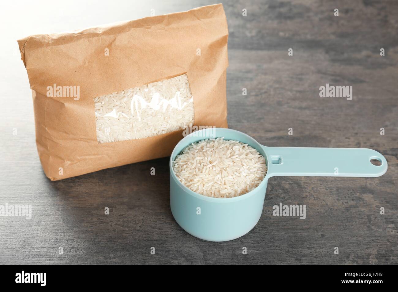 Pack of rice and full measuring scoop on table Stock Photo - Alamy