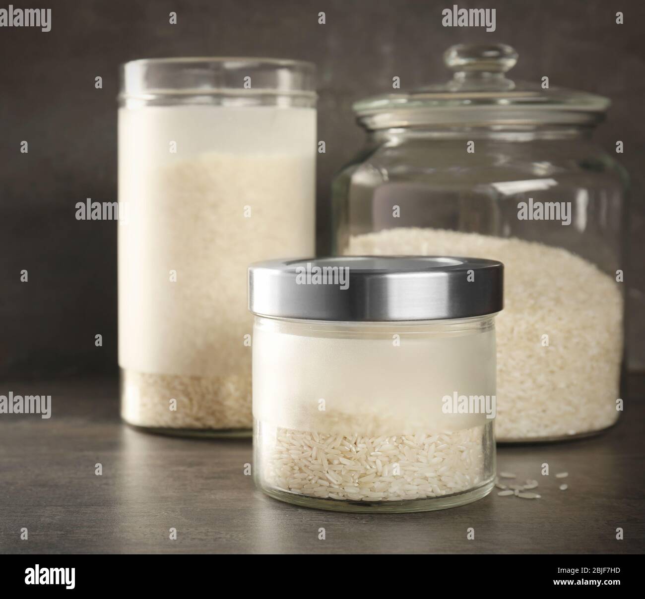 Glass jars with rice on grey table Stock Photo - Alamy