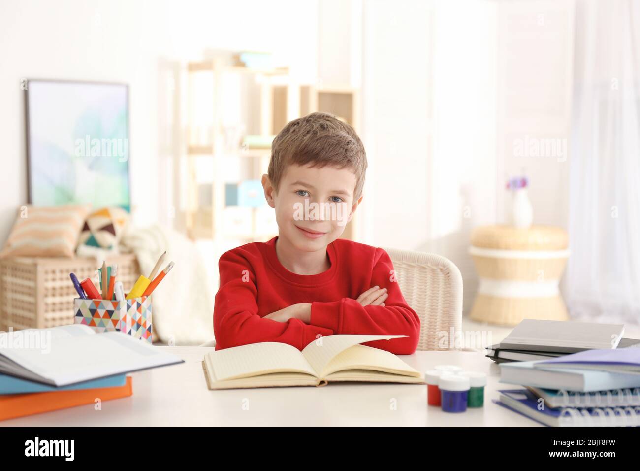 Schoolboy doing homework at table in room Stock Photo - Alamy