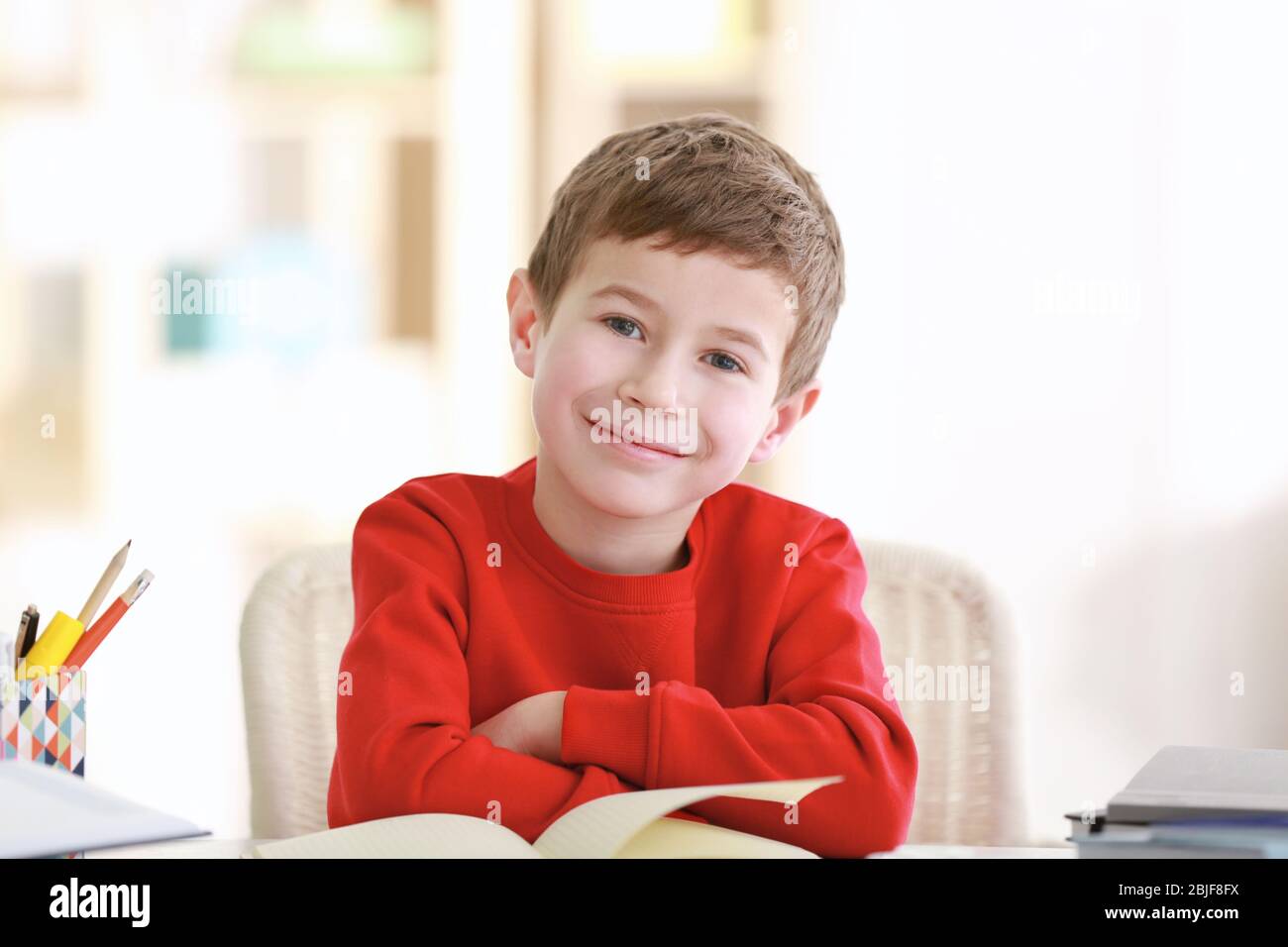 Schoolboy doing homework at table in room Stock Photo - Alamy