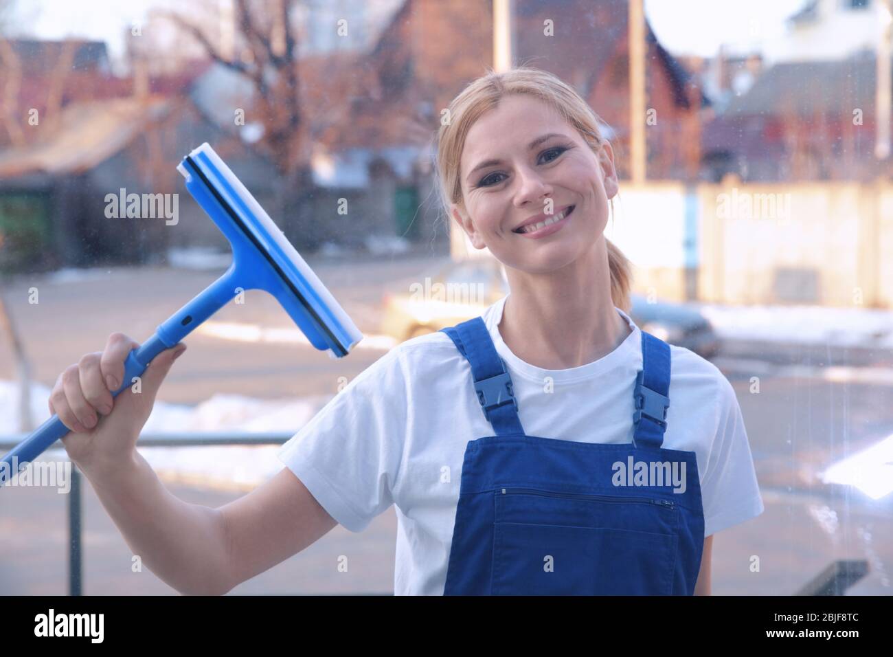 Woman cleaning window with scraper, view through glass Stock Photo - Alamy