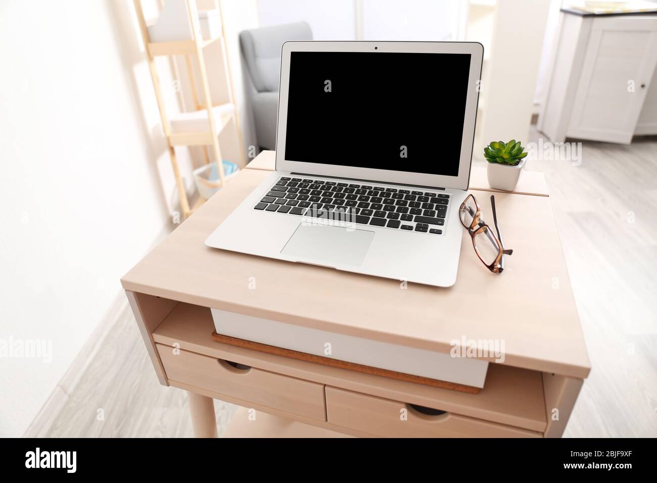 High desk with laptop in room Stock Photo - Alamy