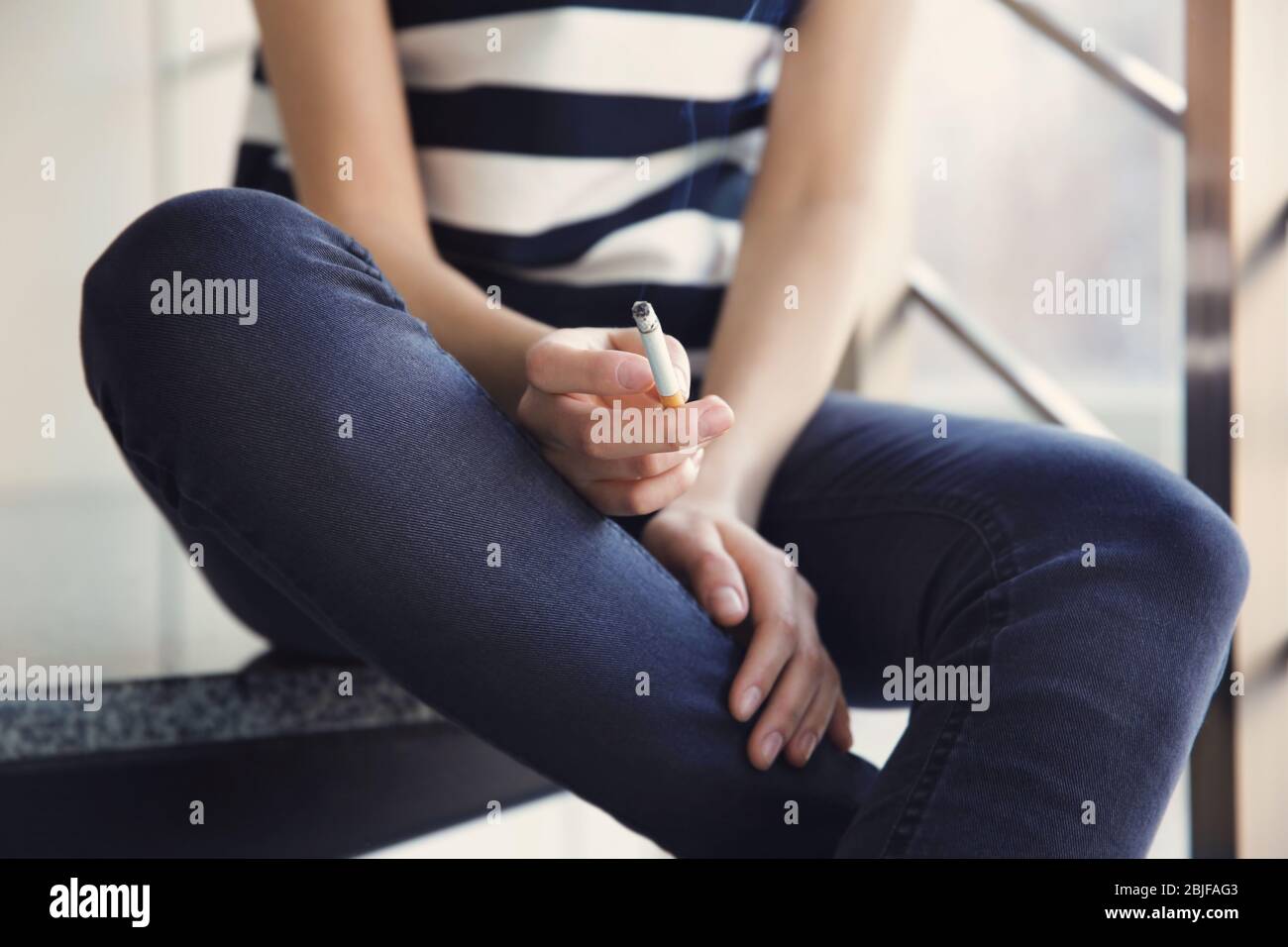 Young woman sitting with cigarette on stairs Stock Photo - Alamy