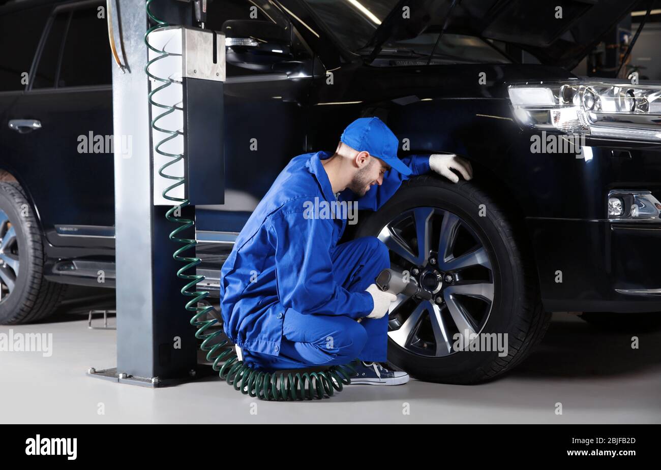 Young mechanic changing wheel in car service Stock Photo - Alamy