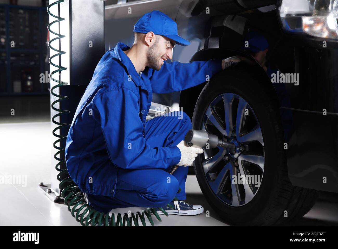 Young mechanic changing wheel in car service Stock Photo - Alamy