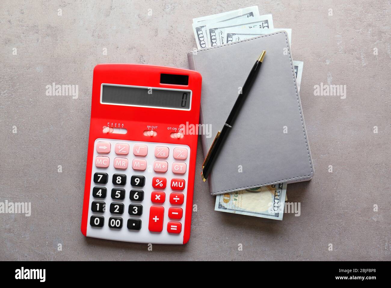 Red calculator and notepad with banknotes on grey background Stock ...