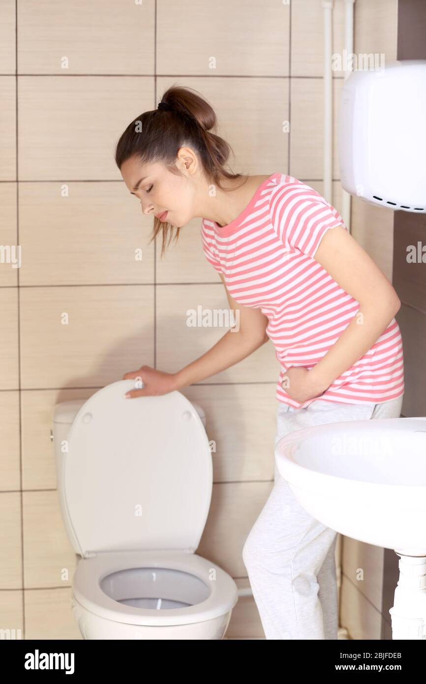 Young vomiting woman near toilet bowl at home Stock Photo - Alamy