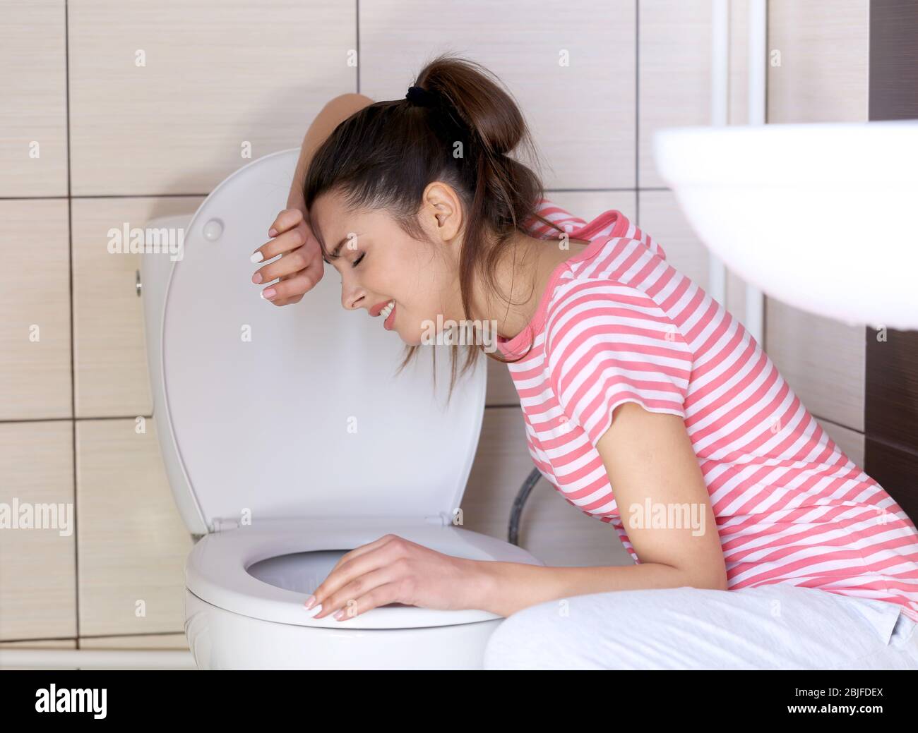Young vomiting woman near toilet bowl at home Stock Photo - Alamy