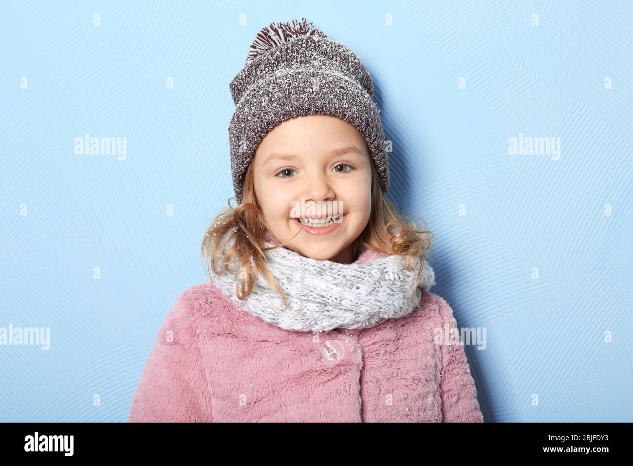 Cute little girl in warm clothes on color background Stock Photo - Alamy