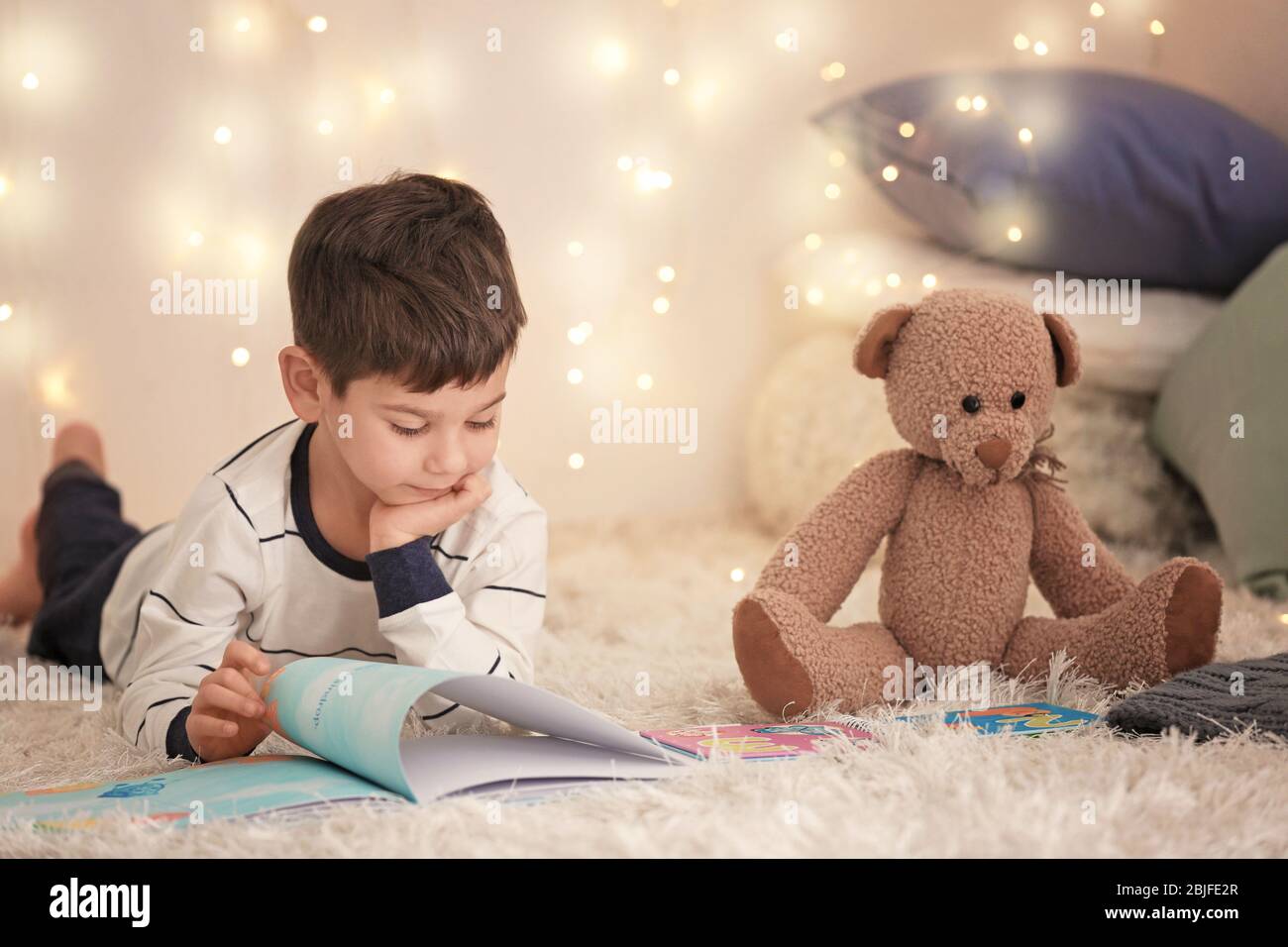 Cute little boy with teddy bear reading book at home Stock Photo - Alamy