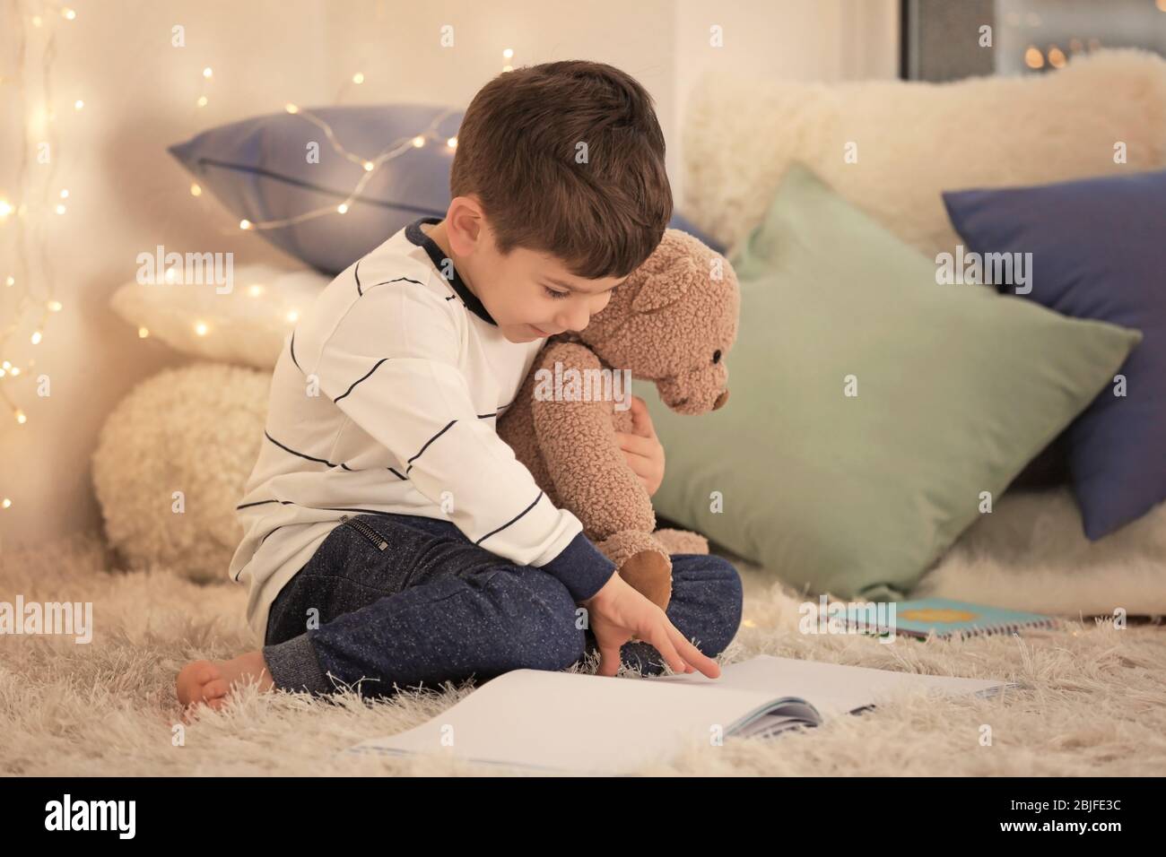 Cute little boy with teddy bear reading book at home Stock Photo - Alamy