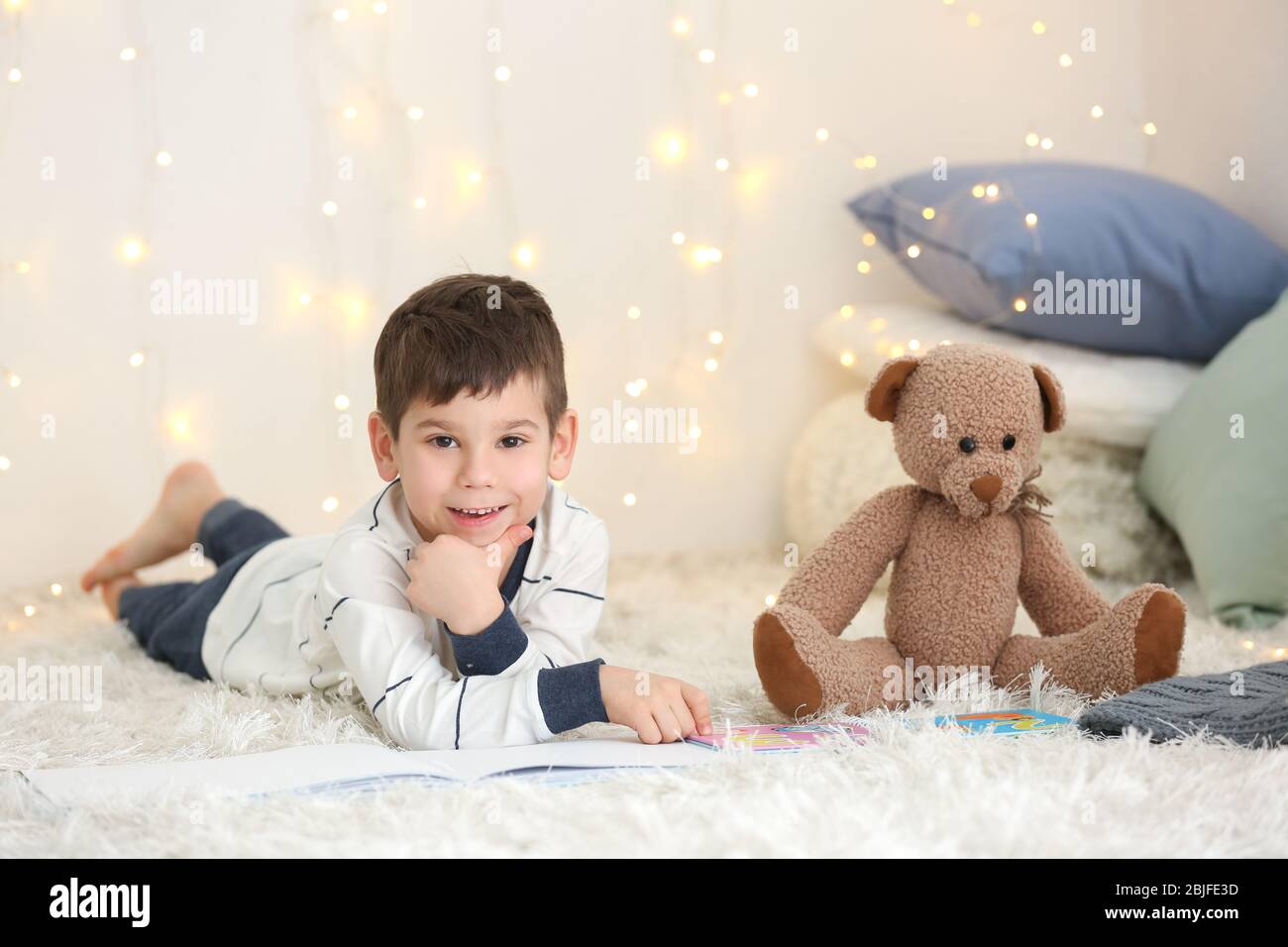 Cute little boy with teddy bear reading book at home Stock Photo - Alamy