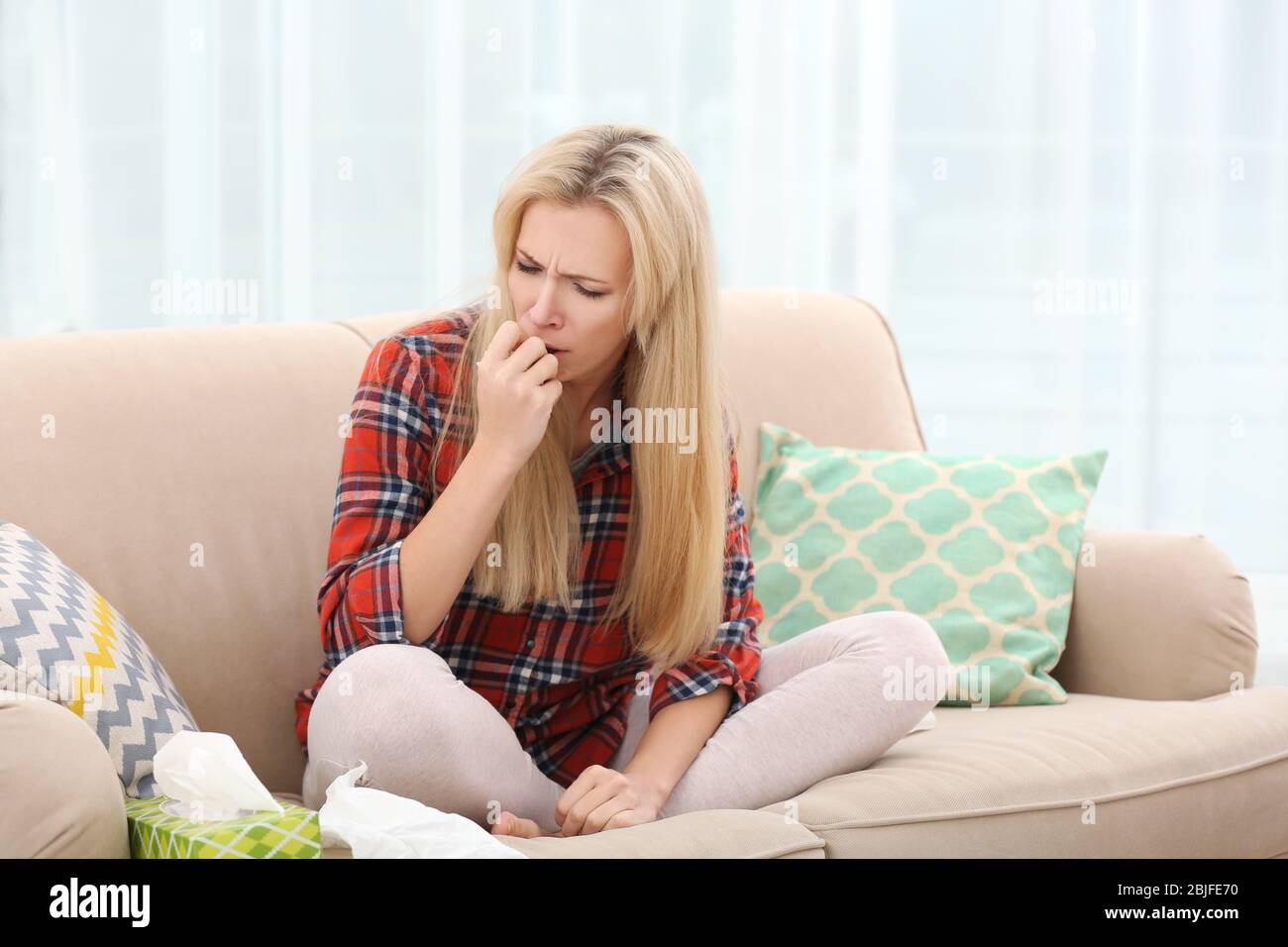 Young woman with allergy sitting on sofa at home Stock Photo - Alamy