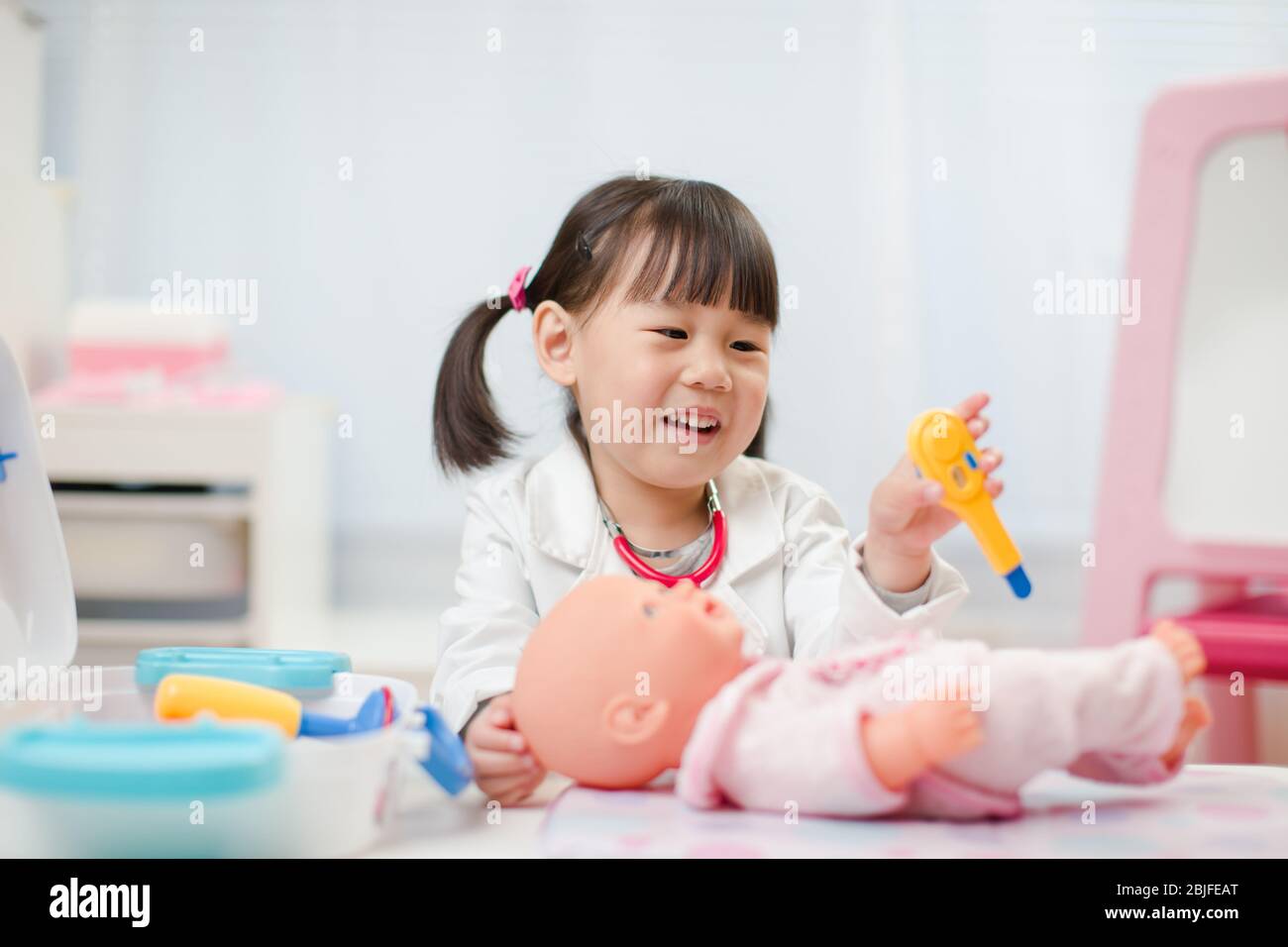 toddler girl pretend play doctor role at home against white background ...