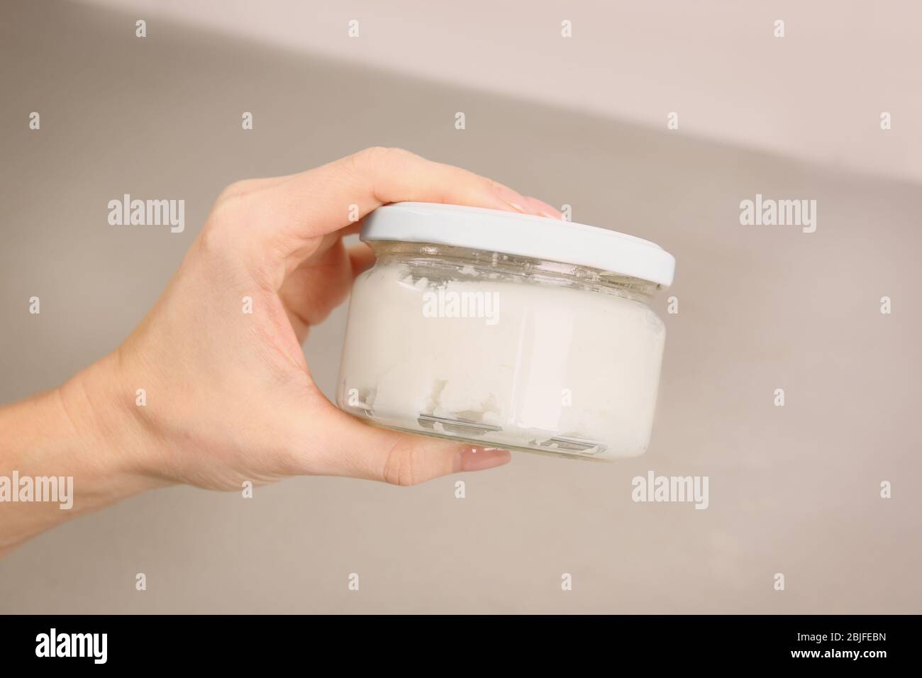 Female hand holding jar with coconut oil Stock Photo - Alamy