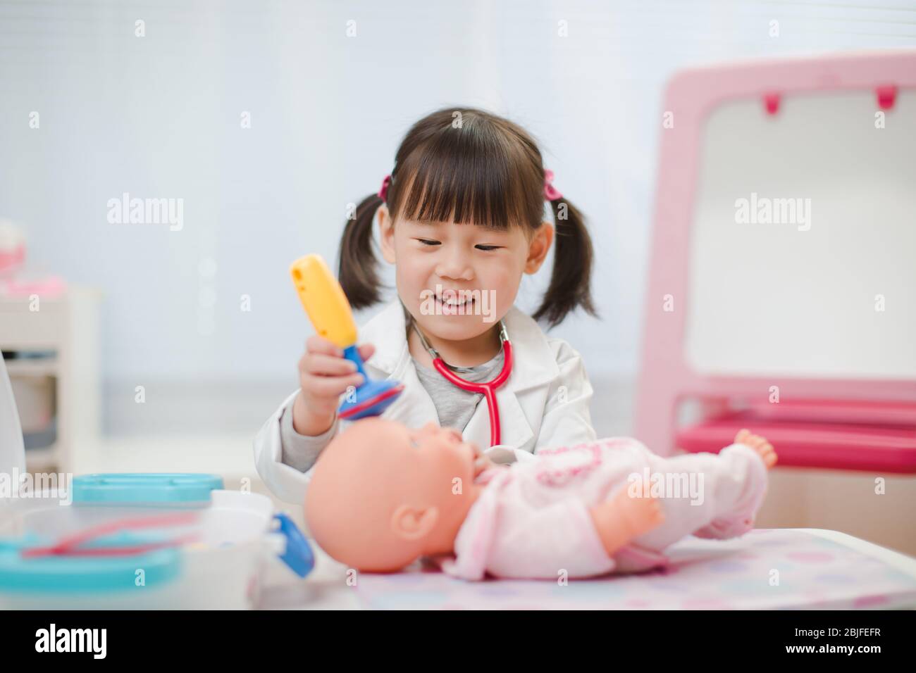 toddler girl pretend play doctor role at home against white background ...