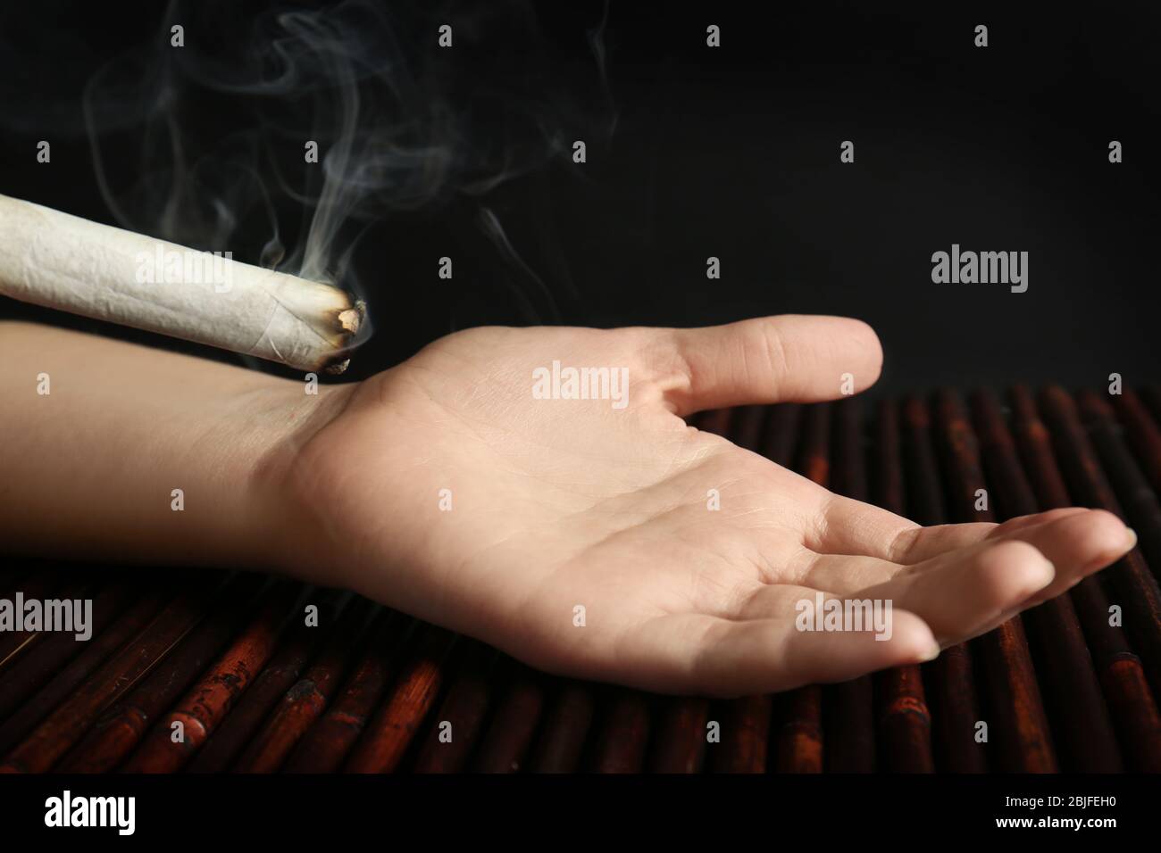 Professional smoking moxa stick with human hand on dark background ...